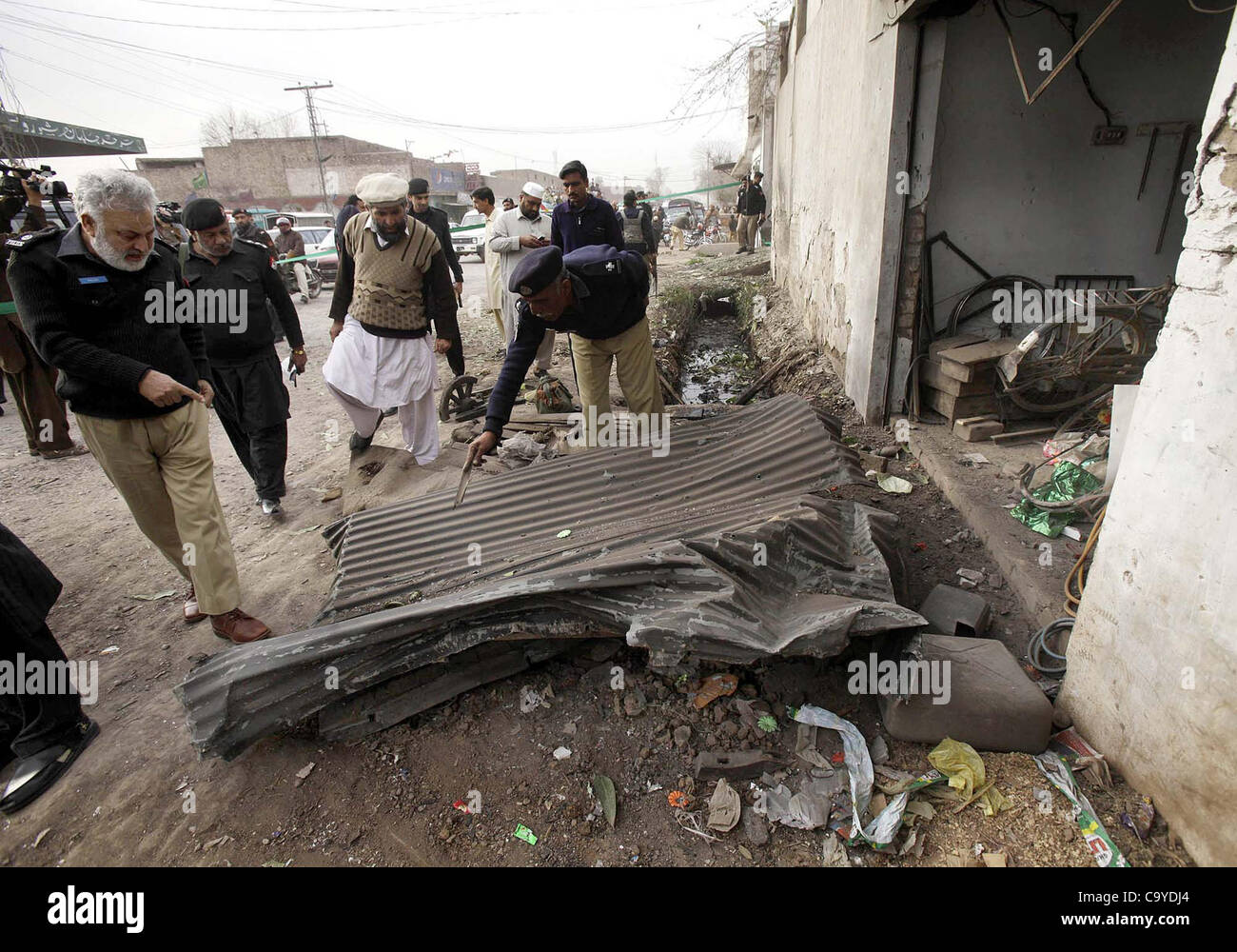 Police officers inspect the site of explosion while damaged shutter of ...