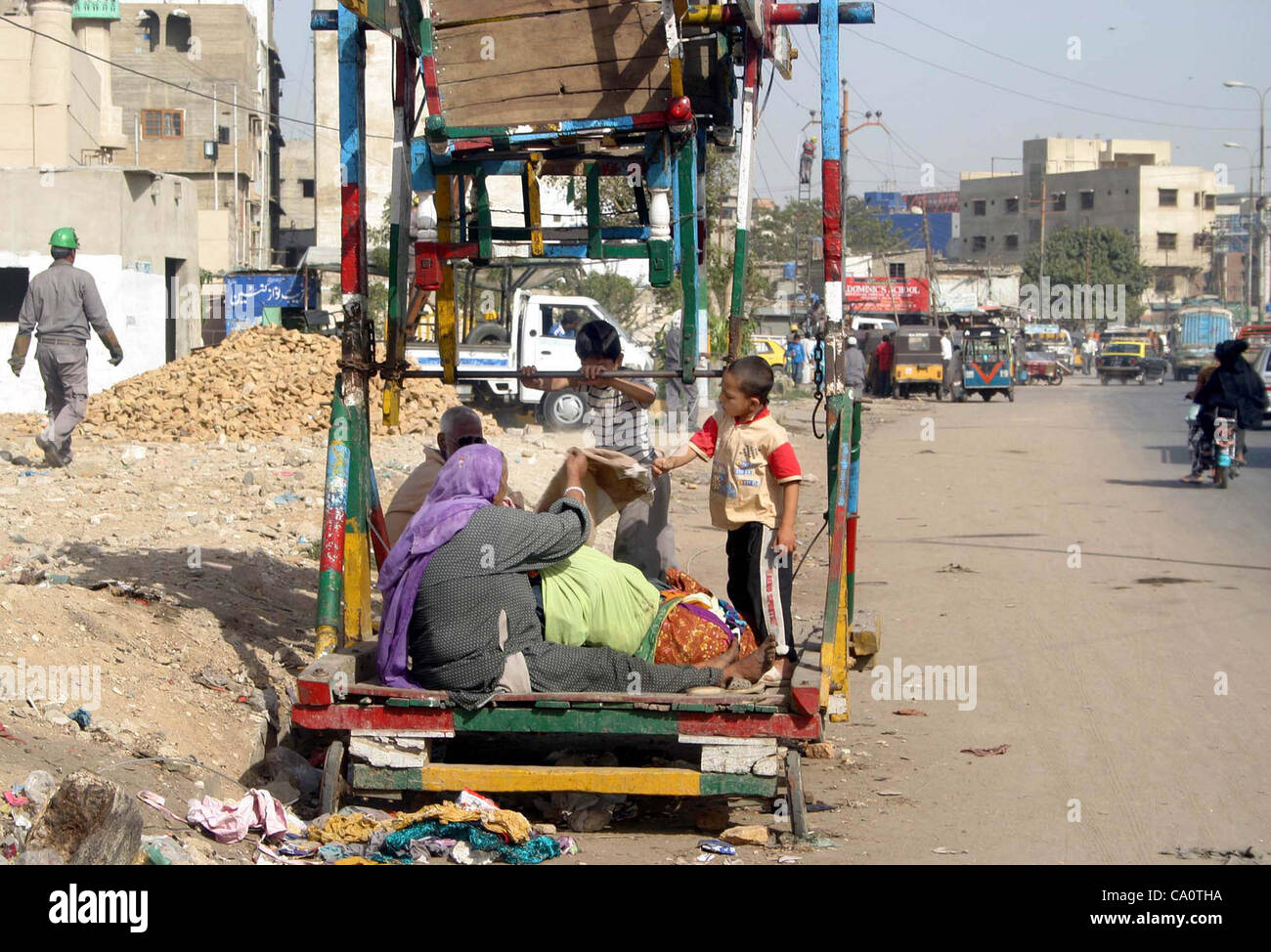 A beggar woman along with children takes rest on a swing at a roadside ...