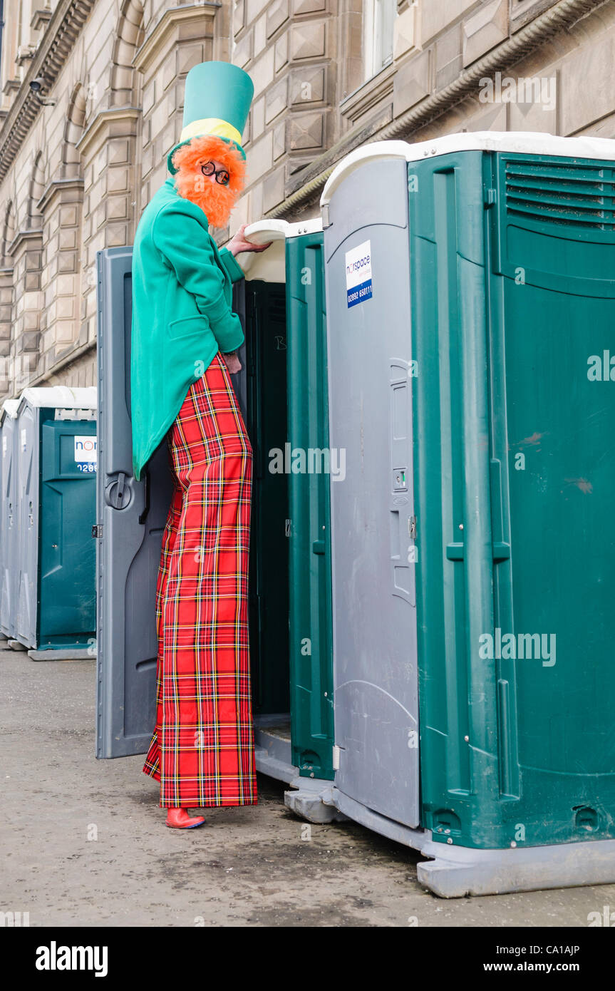 Belfast, UK. 17 Mar, 2012. Stiltwalker pretends to urinate into a Stock ...