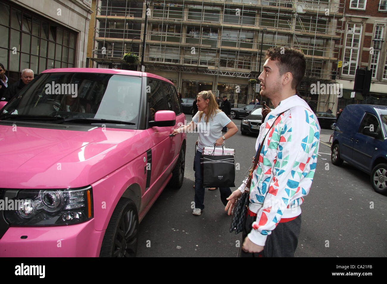 London, UK. 22/03/2012: A man jumps on Katie Price's pink Range Rover ...