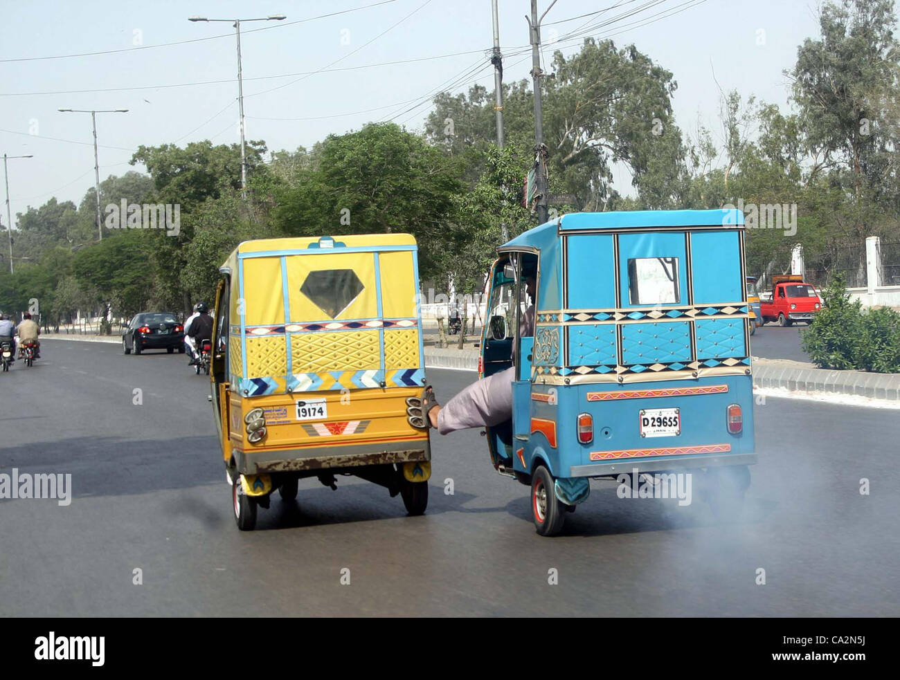 A rickshaw driver tows a closed auto-rickshaw passes through MA.Jinnah ...