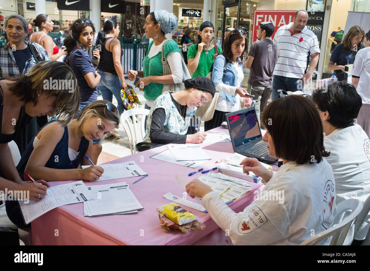 Volunteer donors line up to register for giving saliva samples to be ...