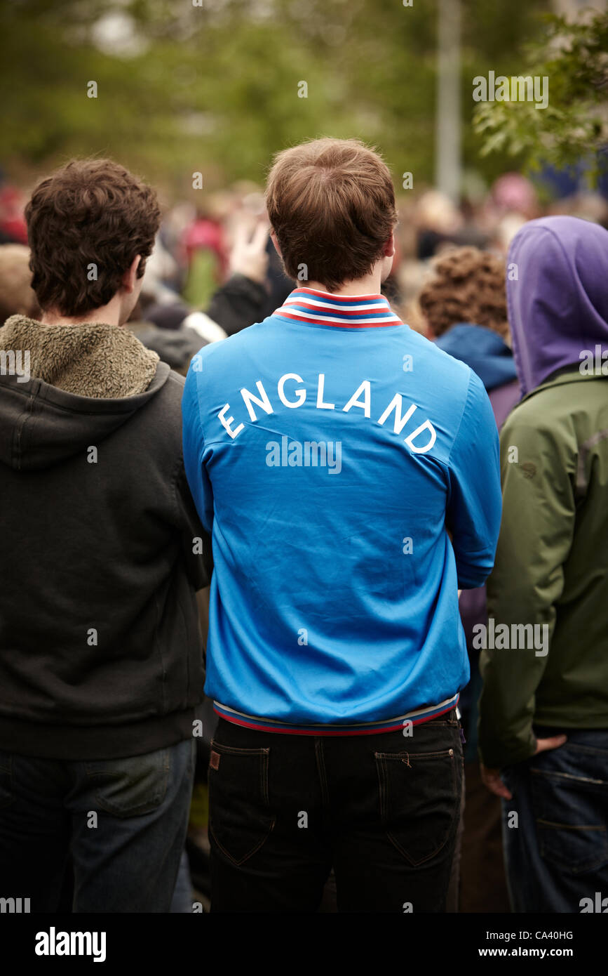 three young men stand watching the Thames river pageant. One has an ...