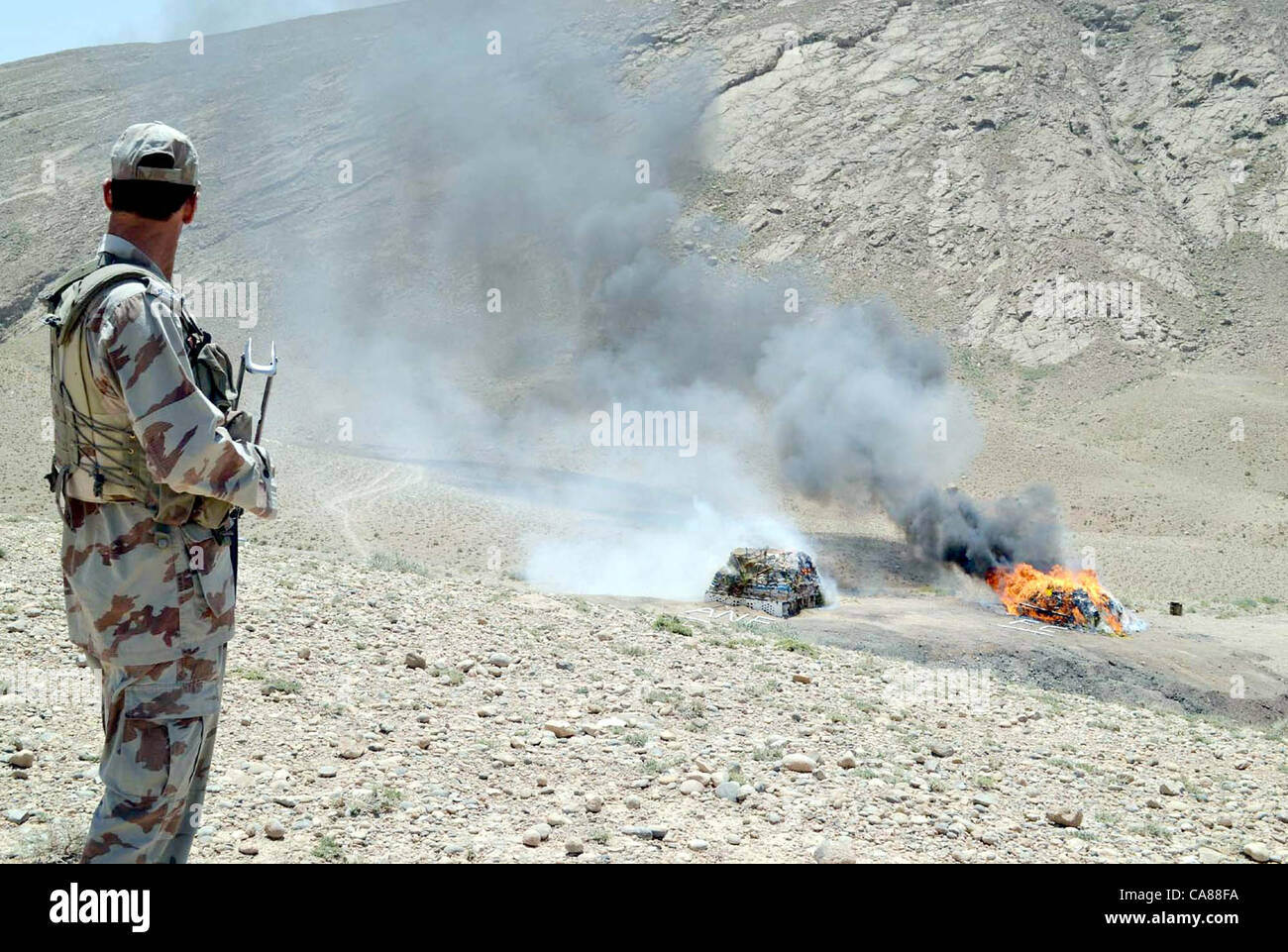 A soldier stands alert near burning piles of confiscated drugs during ...