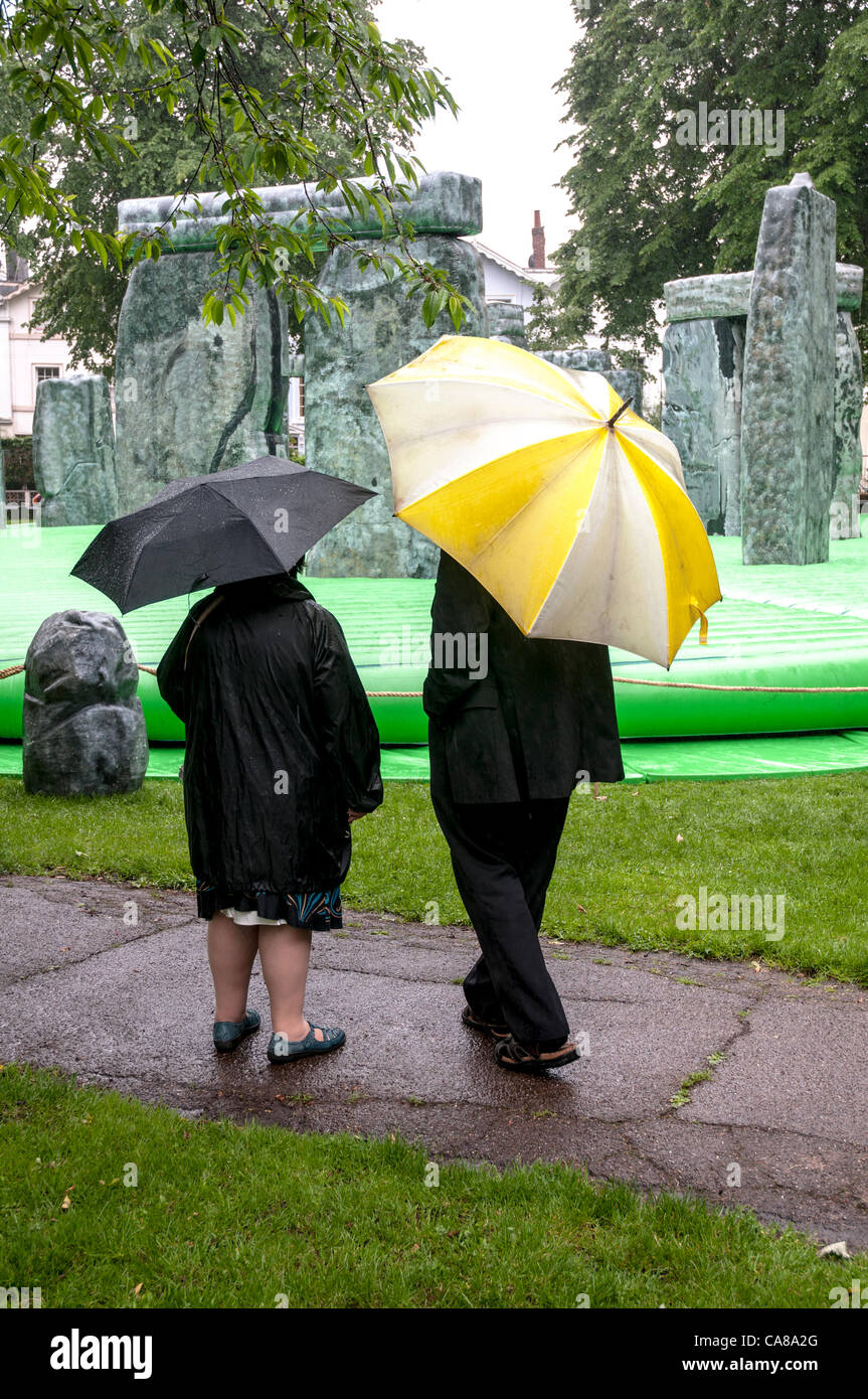 Two people stand in the rain with unbrella's and look at life-sized ...