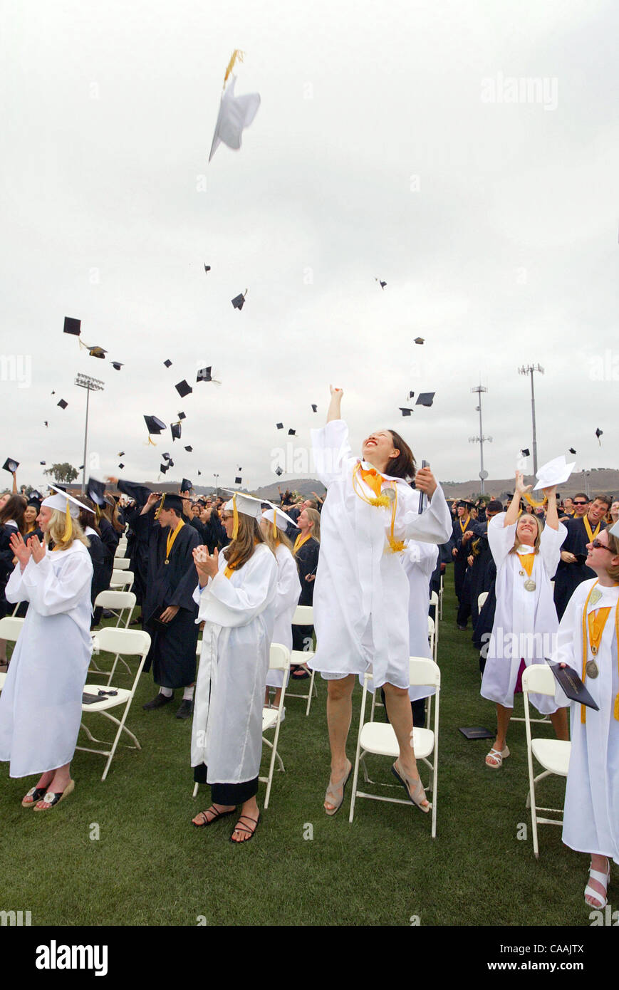 National Merit Society graduates in distinctive white gowns toss their ...