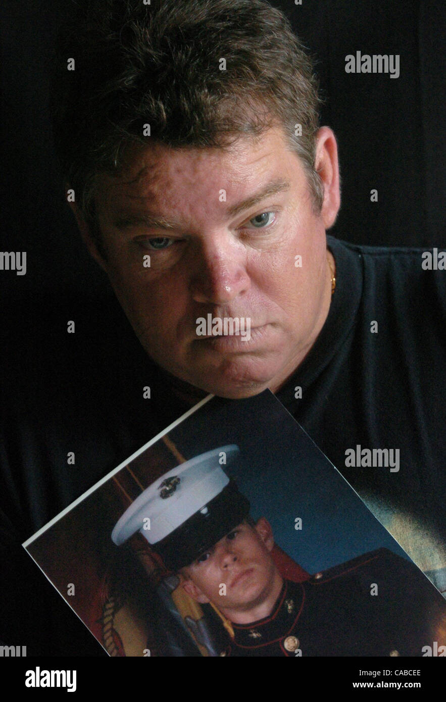 Mark Crowley (cq), father of Kyle Crowley (cq), poses with photos of ...