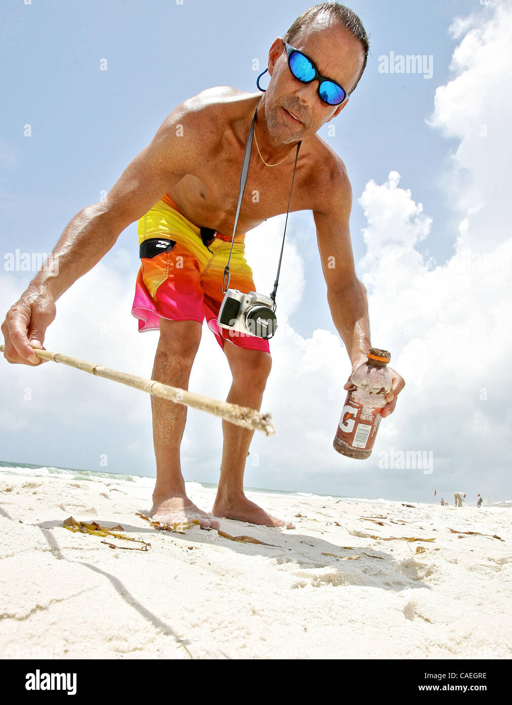 Resident Patrick Mulcahy tries to scoop up little bits of oil into a ...