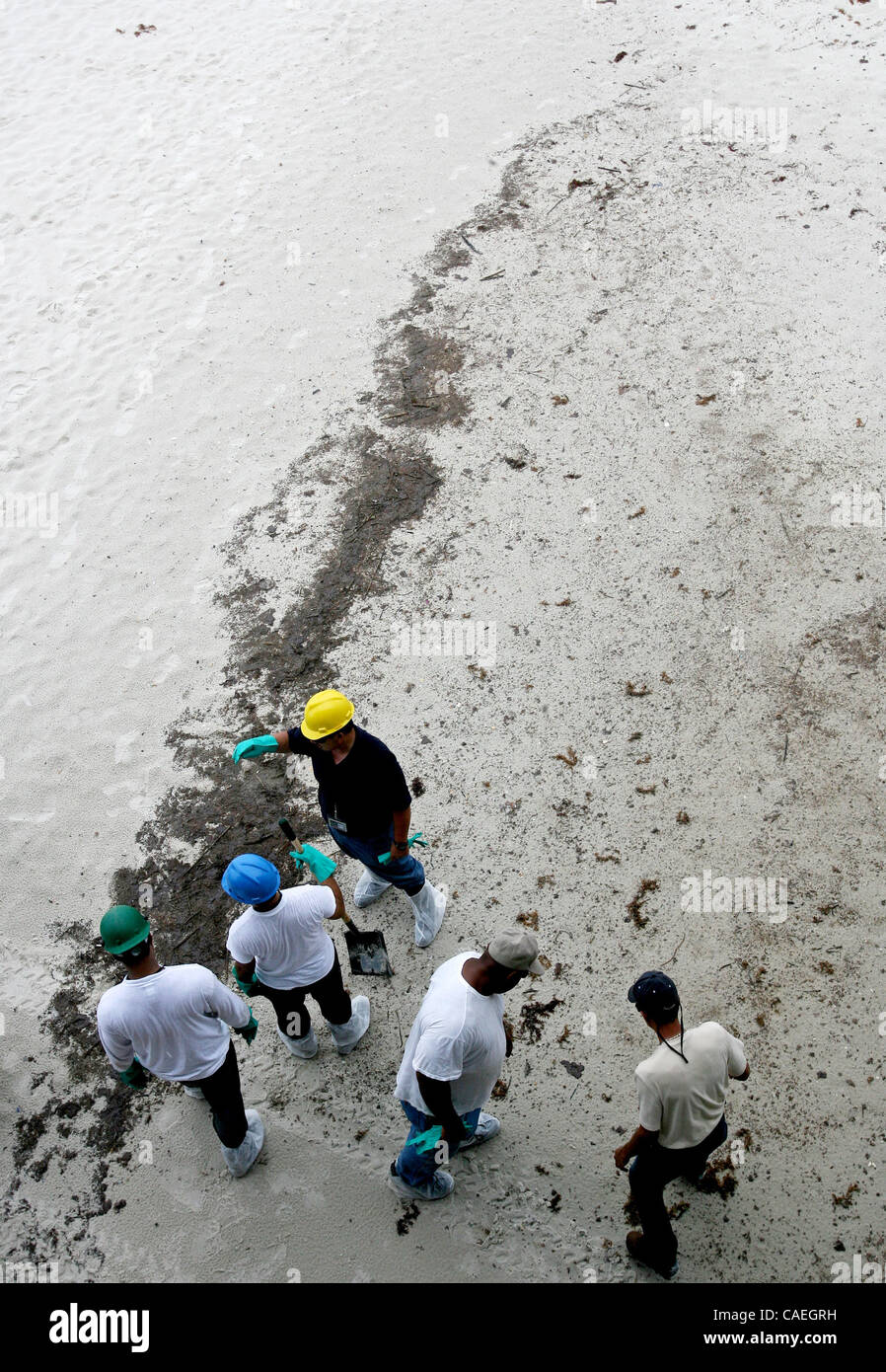 Clean up crews work to scoop up oil on the beach after a break from a ...