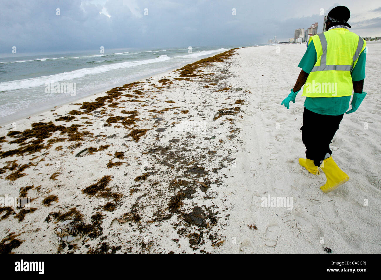 A member of a clean up crew walks the oil covered shoreline on the ...