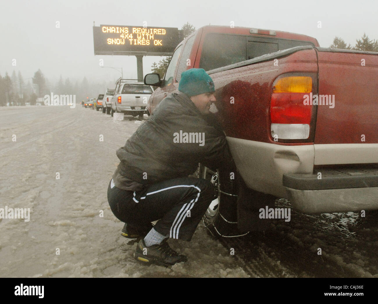 Hayden McCawe, San Jose, puts snow chains on his truck along Highway 50 ...