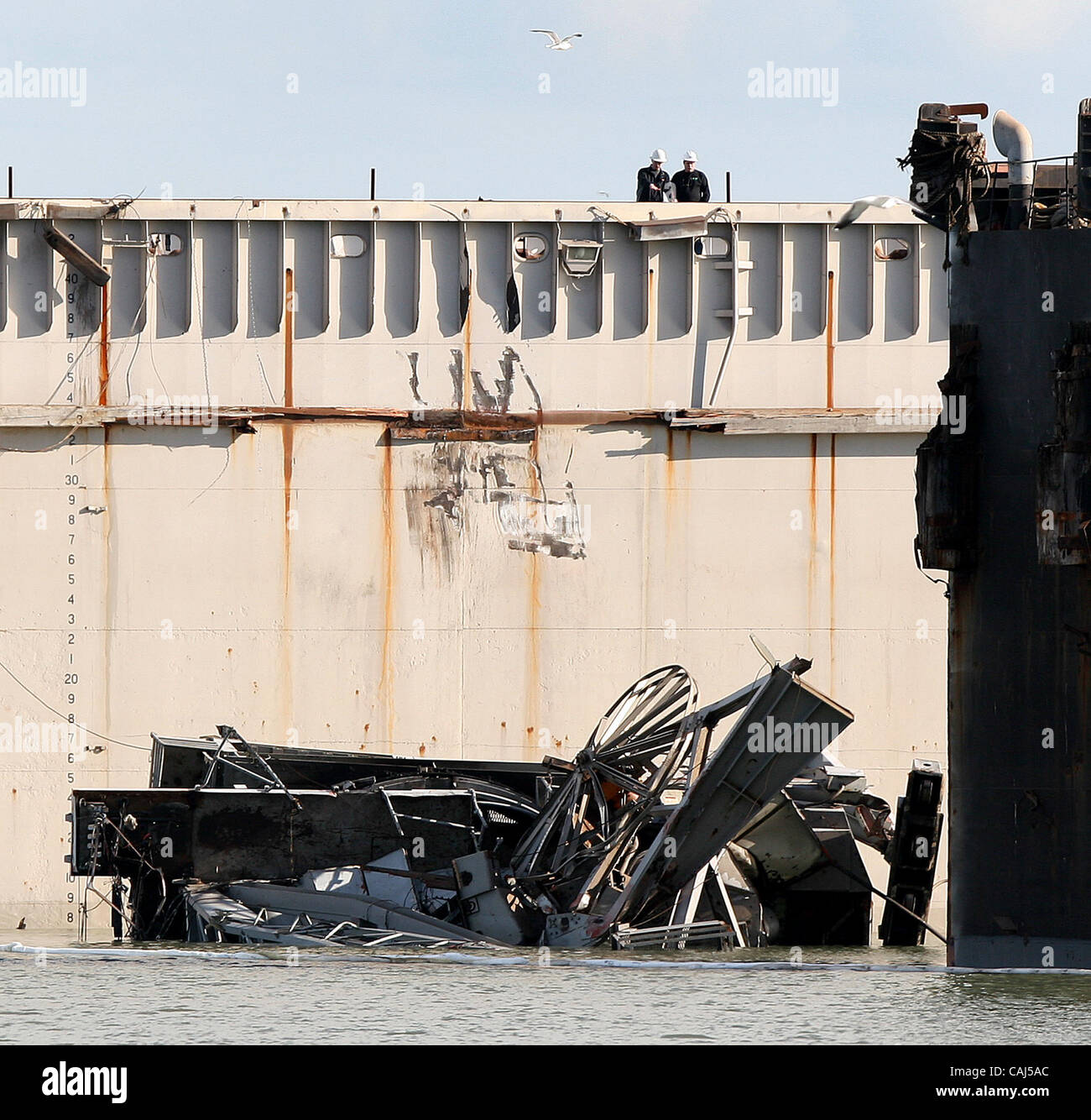 Workers survey the scene of a crane collapse off a dry dock at pier 70 ...