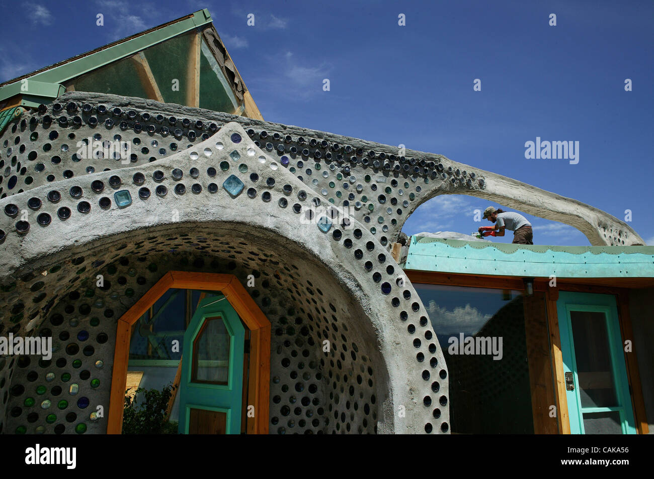 A worker performs exterior finishing work on an Earthship in the ...