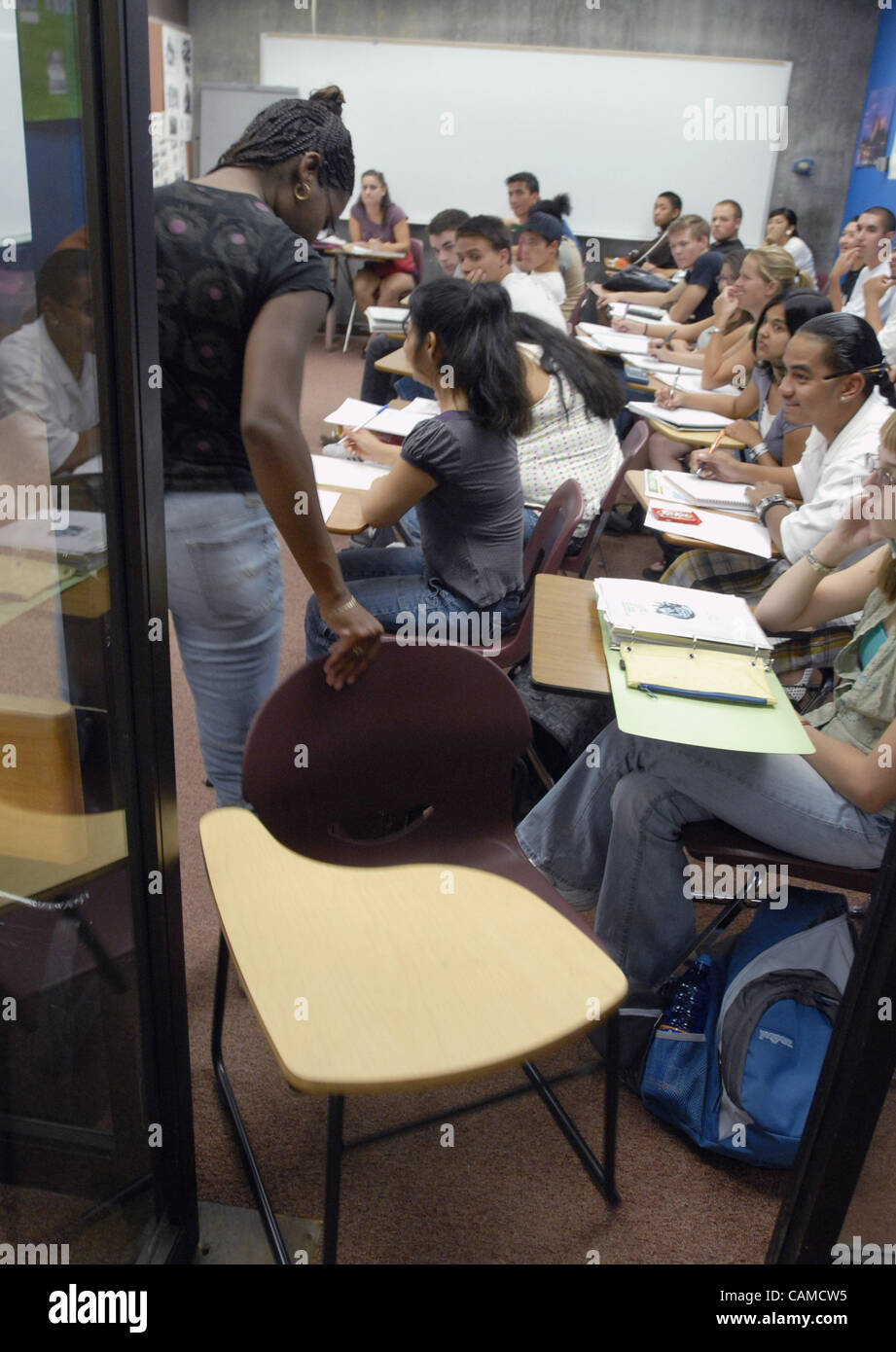 A student squeezes one more desk into an already crowded class room in ...