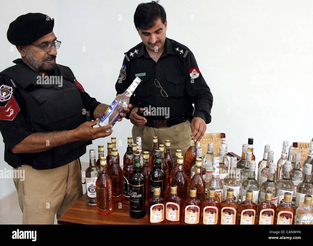 Police officers inspect seized liquor bottles which were allegedly ...