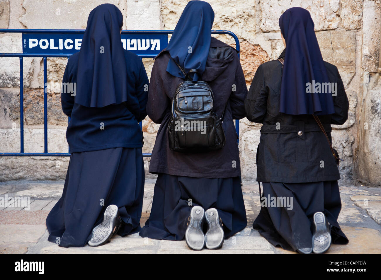 Three nuns kneel in prayer near the Holy Sepulchre Church. Jerusalem ...