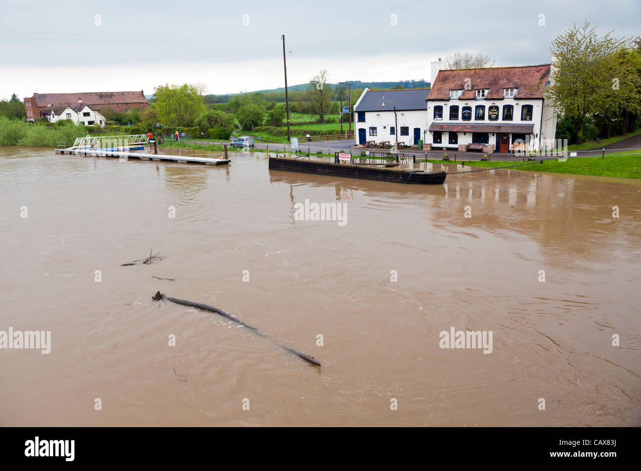 Flood debris floating down the River Severn passing the Haw Bridge Inn ...