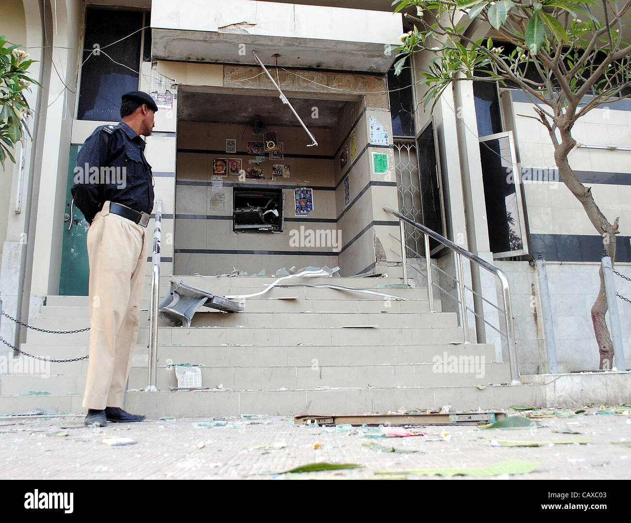 A police officer inspects the damaged portion of a branch of National ...