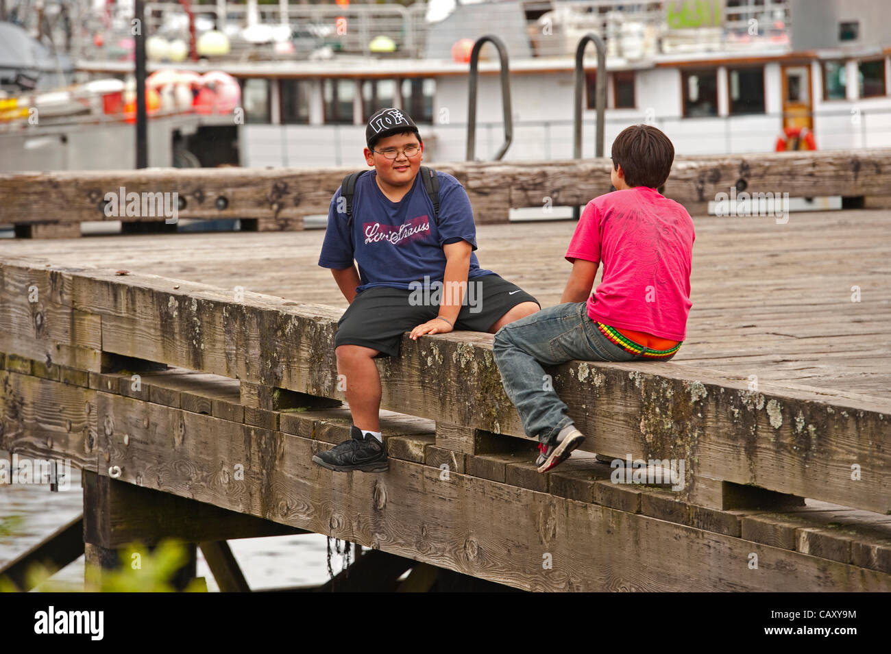 Sitka, Alaska, 5 May 2012 Alaskan Native boys sitting and talking dock ...