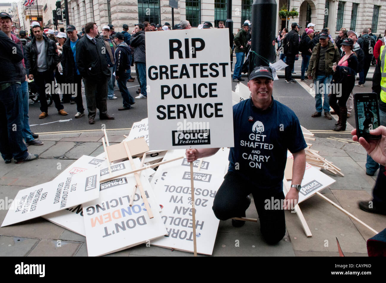London, UK. 10/05/12. An off duty officer holds up a banner during ...