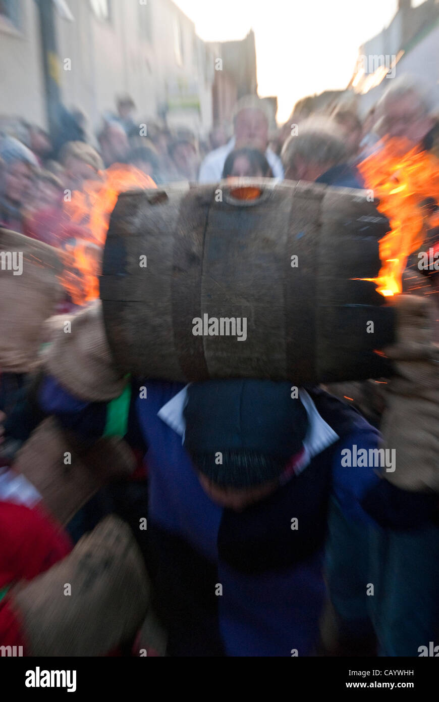 A young barrel roller runs through the crowd with a burning barrel at ...