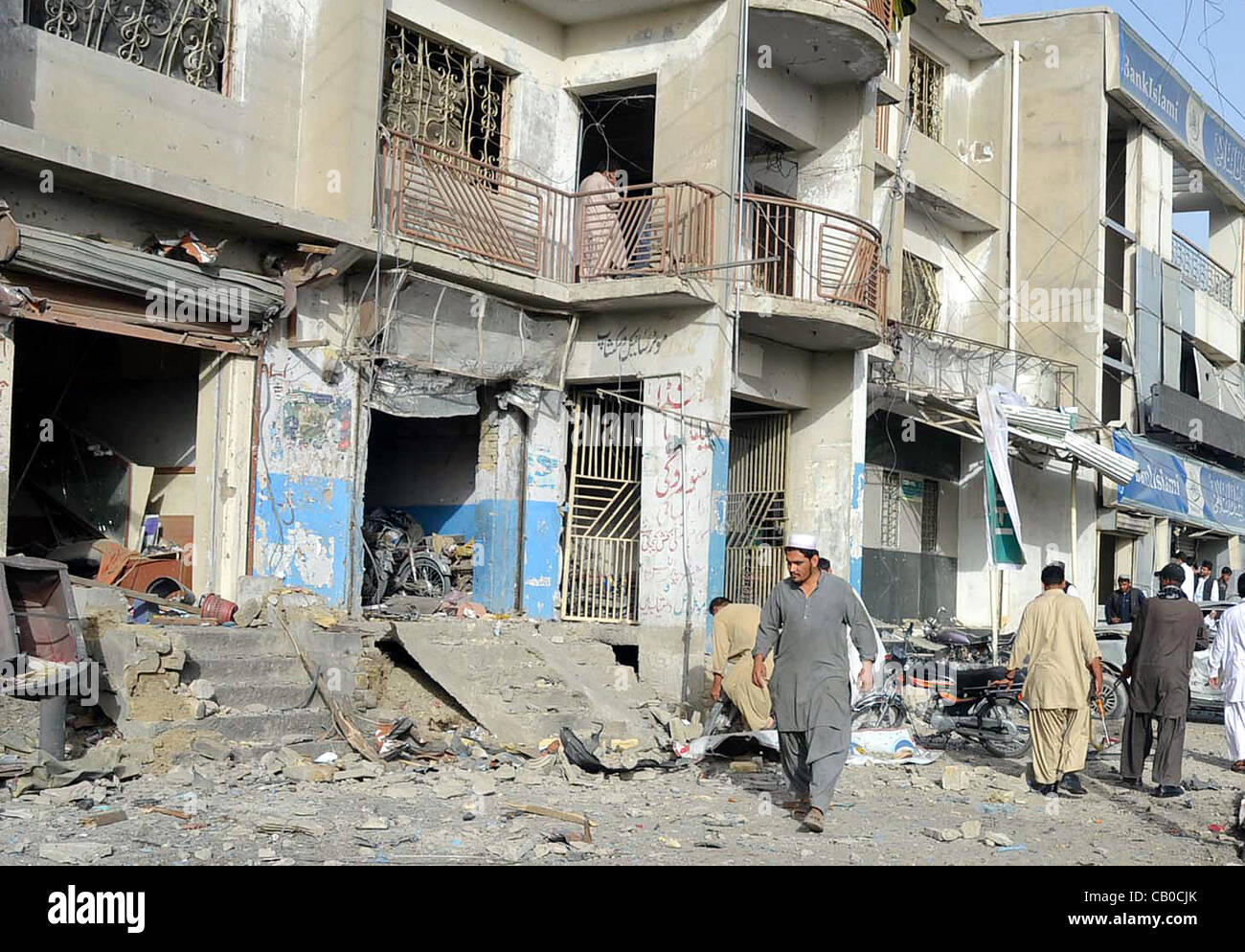 People gather at the site of explosion while damaged shops, which were ...