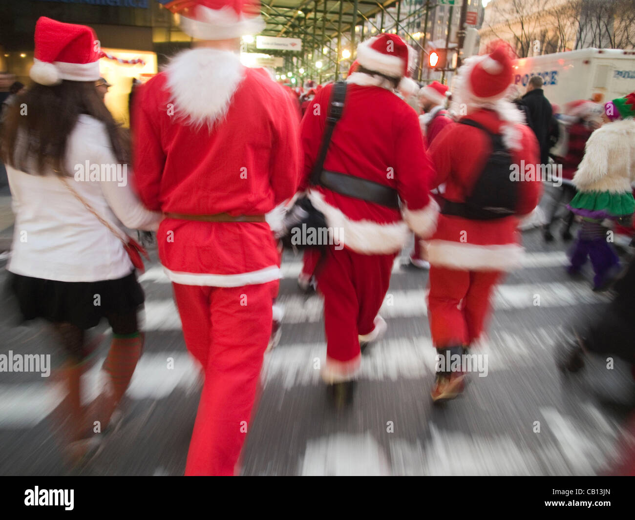 Several Santas walk arm and arm down the street during Santa Con, an ...