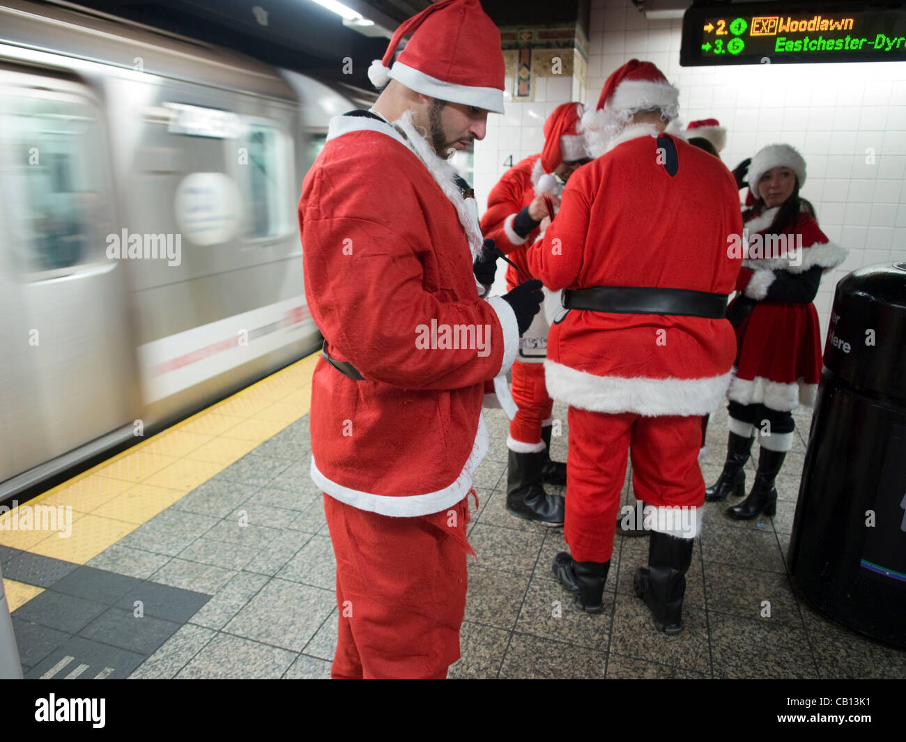 Santa Clauses wait in subway station during Santa Con, an annual pub ...