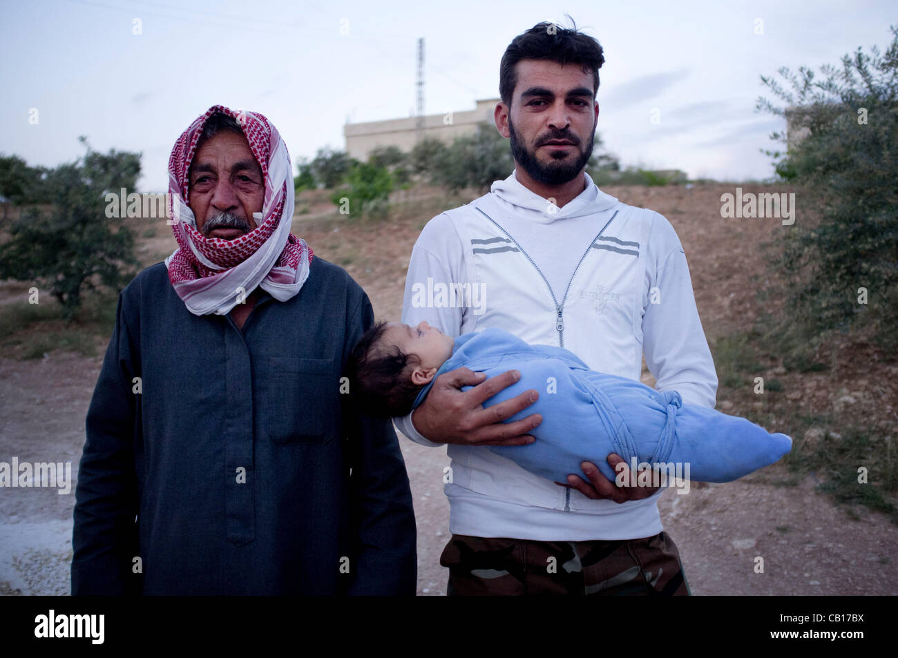 A Syrian man (name withheld) stands next to his father, holding his ...