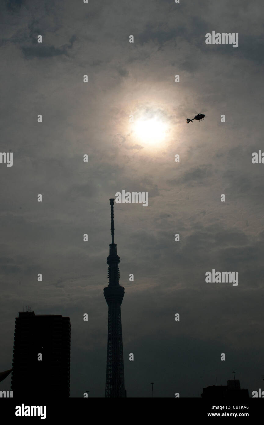 A helicopter flies in front of Tokyo Sky Tree as the moon passes in ...