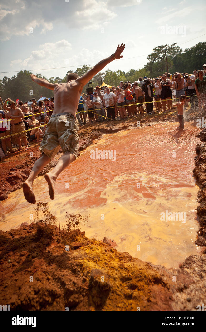 A competitor in the Summer Redneck Games takes a belly flop into a mud ...