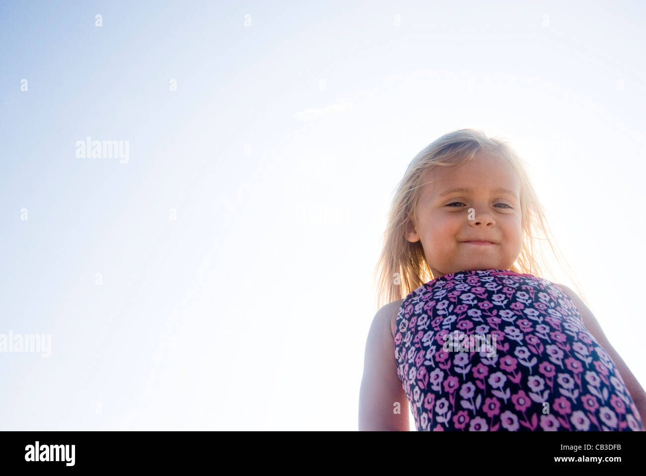 Low-angle portrait of a young girl in a swimsuit, smiling against a ...