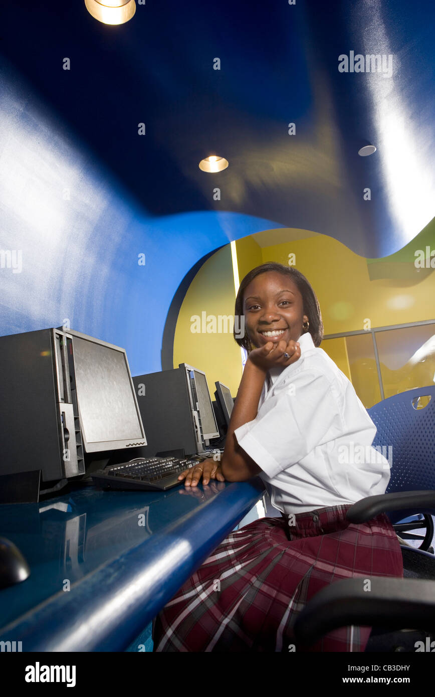 High school student wearing a uniform sitting alone in a computer lab ...