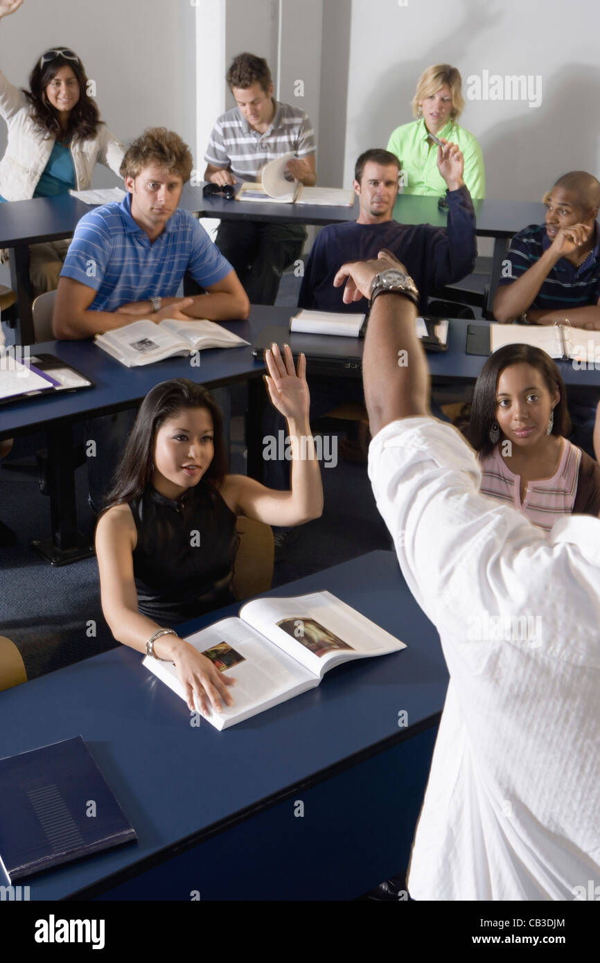 Students raising hands in the classroom Stock Photo - Alamy