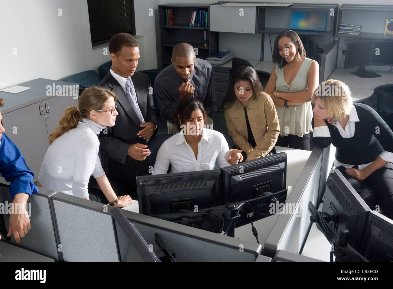 Group of young workers in office gathered around computer screen Stock ...