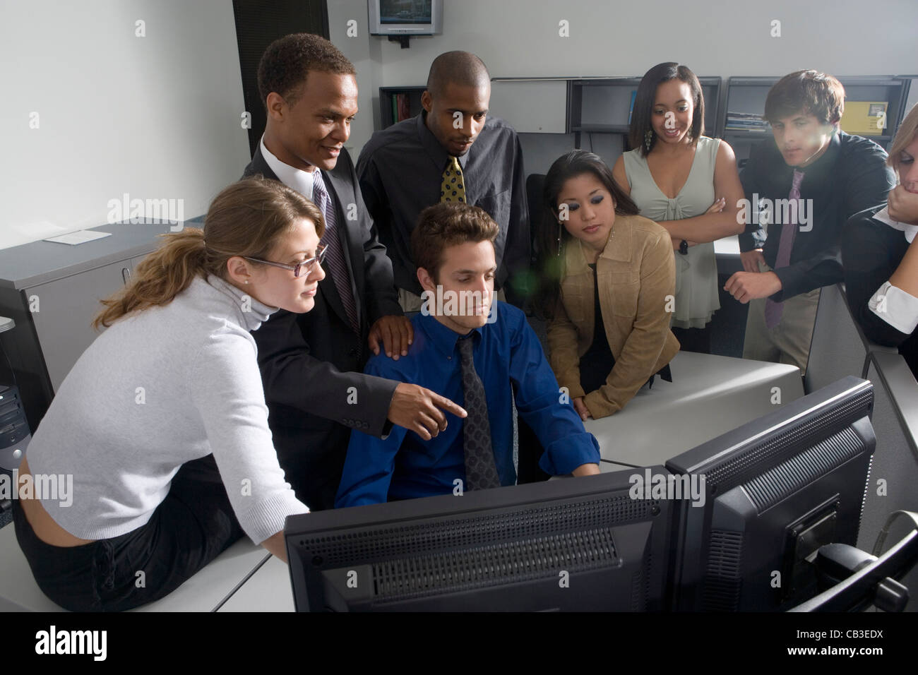 Group of young workers in office gathered around computer screen Stock ...