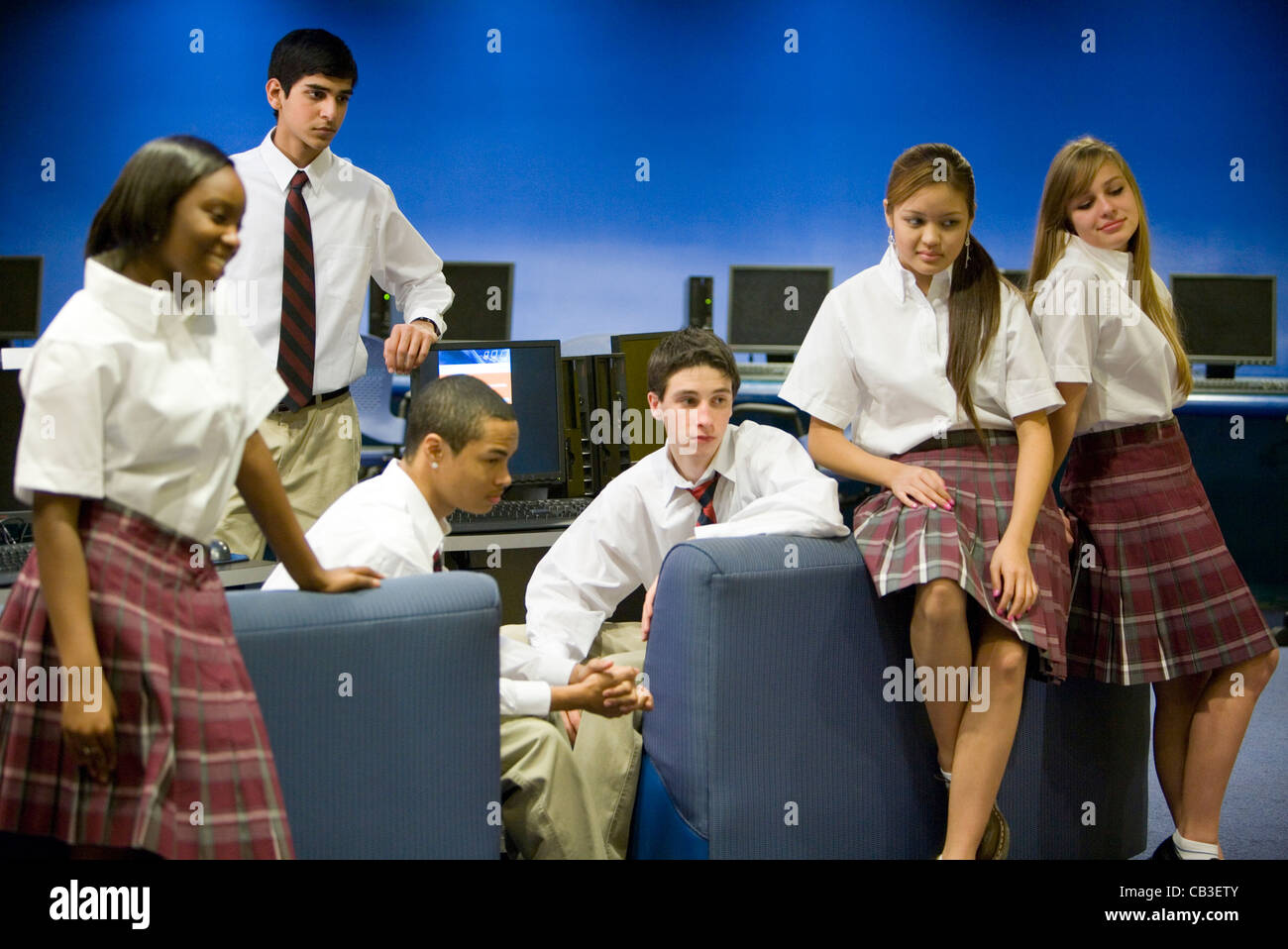 Teenage boy and girl students wearing uniforms sitting together in the ...