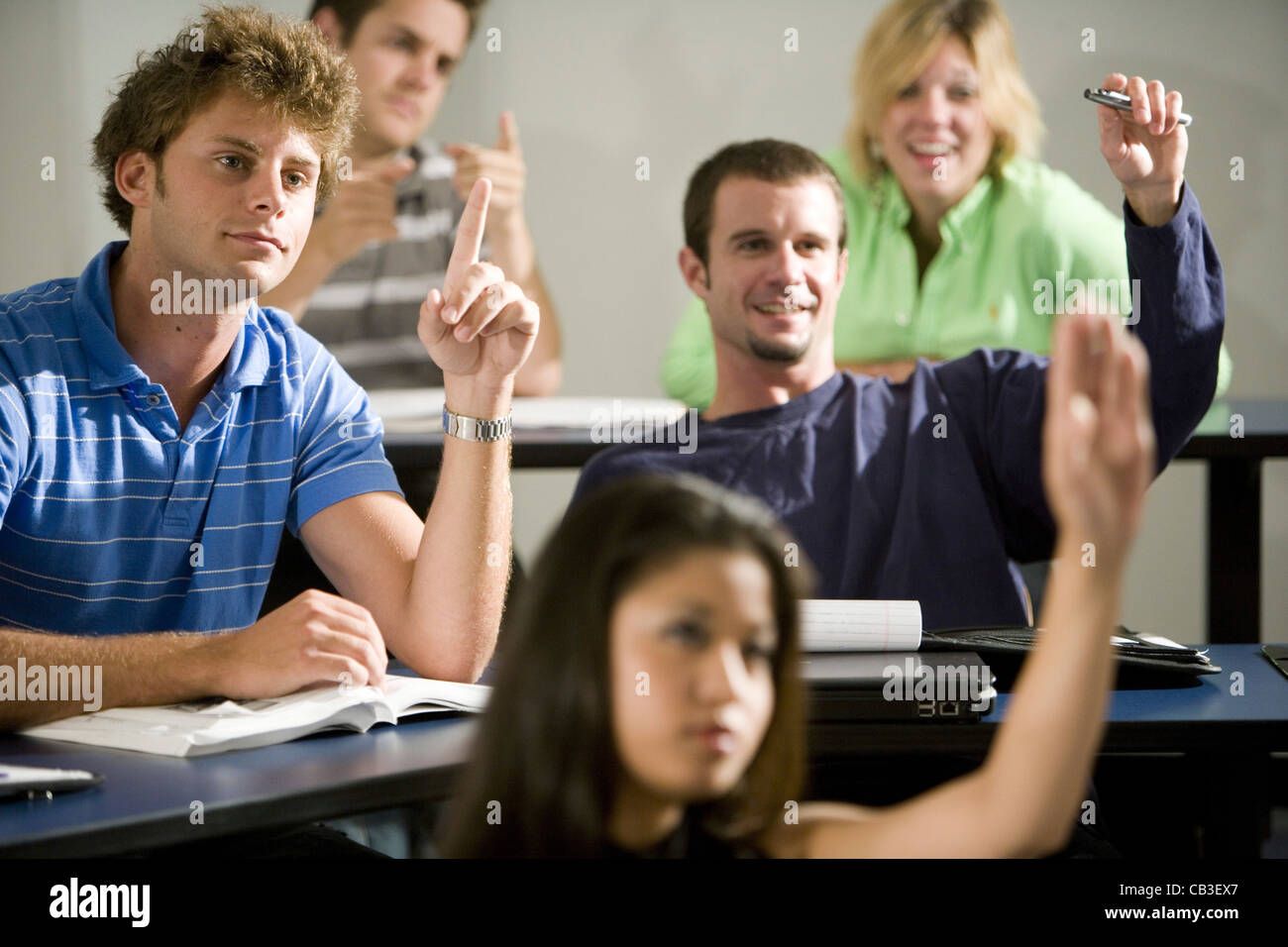 Students raising hands in the classroom Stock Photo - Alamy