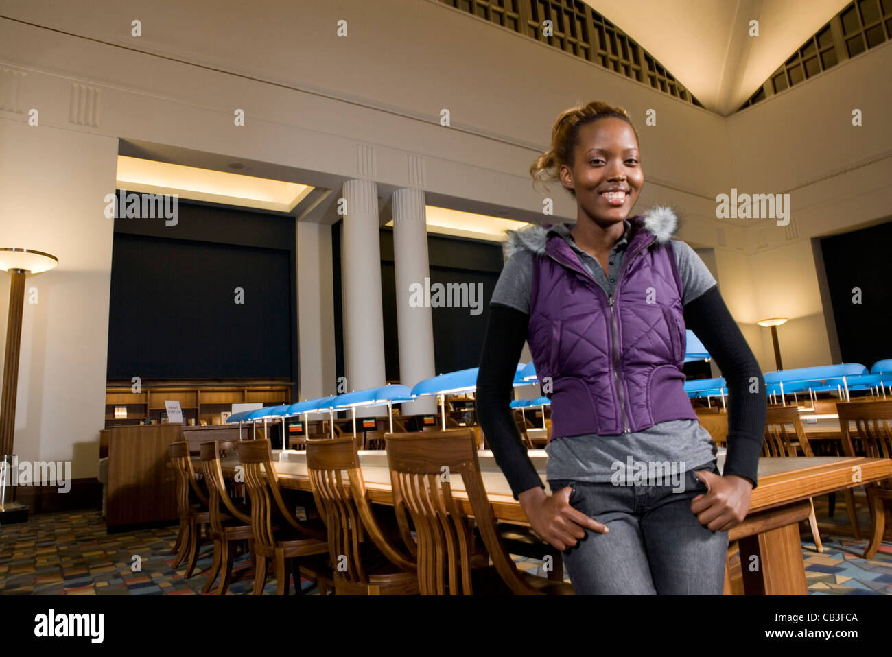 Portrait of a young woman standing in the reading room of a library ...