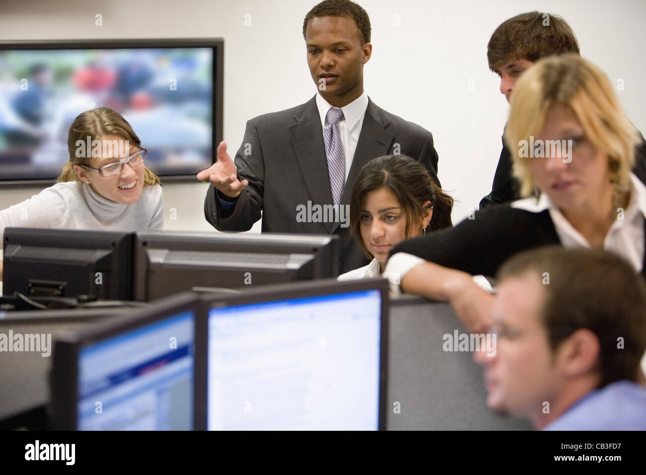 Office workers gathered around computer screens Stock Photo - Alamy