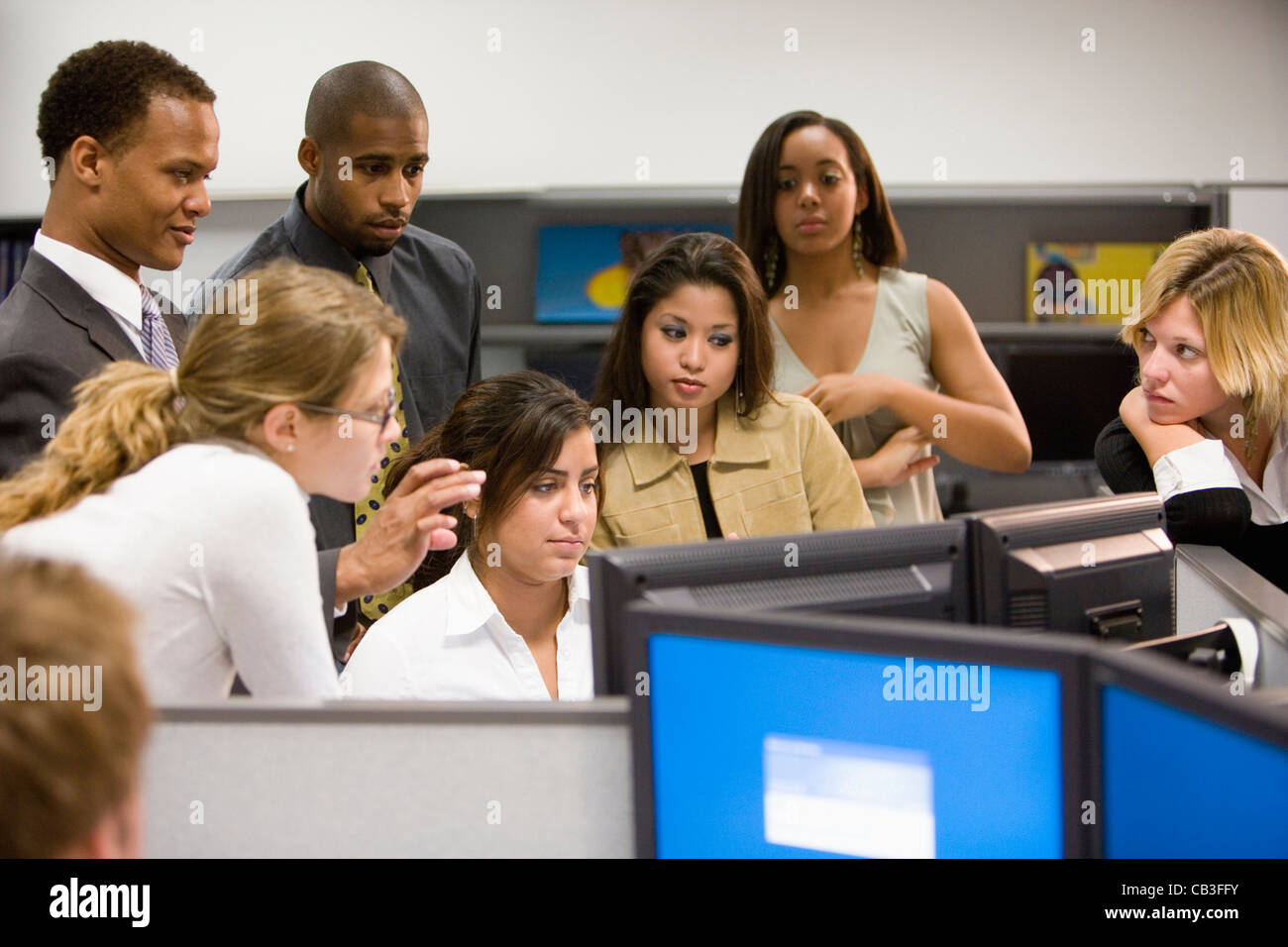 Close-up of office workers gathered around computer Stock Photo - Alamy