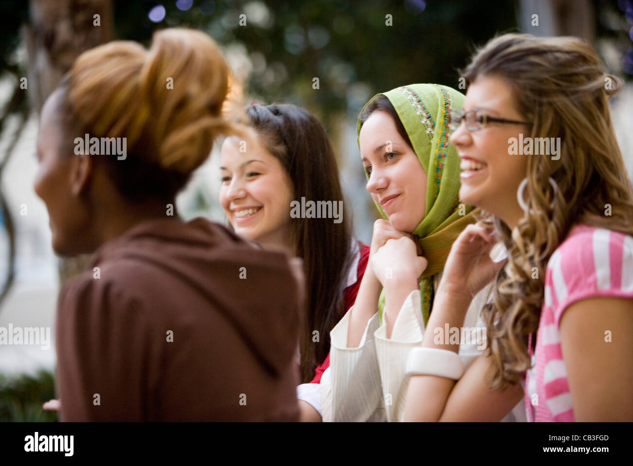 View of four young women conversing while sitting at table in a garden ...