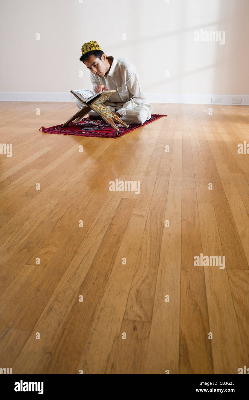 A Muslim man reading Koran on a prayer mat Stock Photo - Alamy