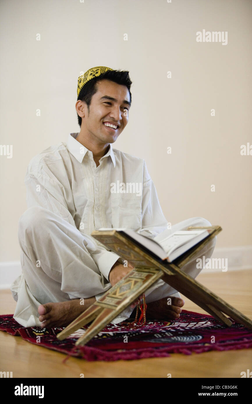 A Muslim man reading Koran on a prayer mat Stock Photo - Alamy