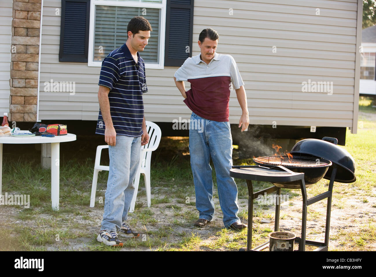 Two men preparing a cookout in front of trailer home Stock Photo - Alamy