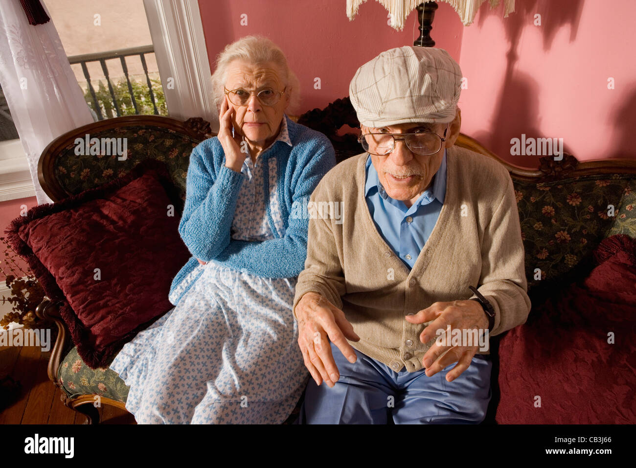 Grumpy senior couple sitting on sofa in living room Stock Photo - Alamy