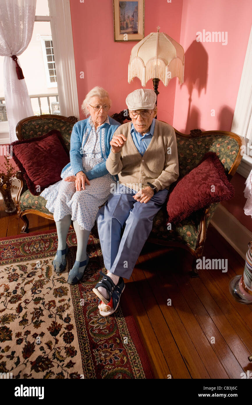 Grumpy senior couple sitting on sofa in living room Stock Photo - Alamy