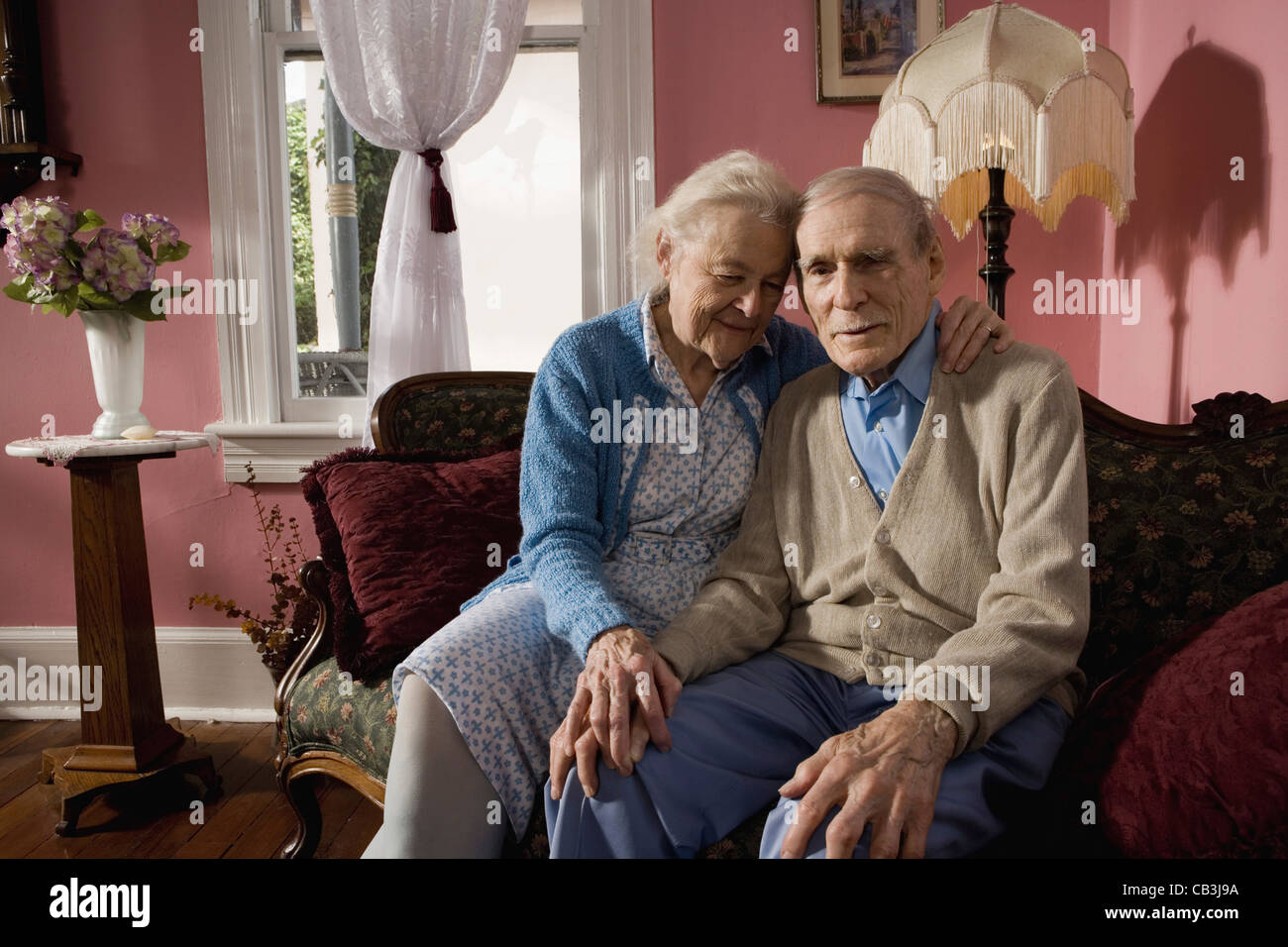 Stoic senior couple sitting on sofa in living room Stock Photo - Alamy