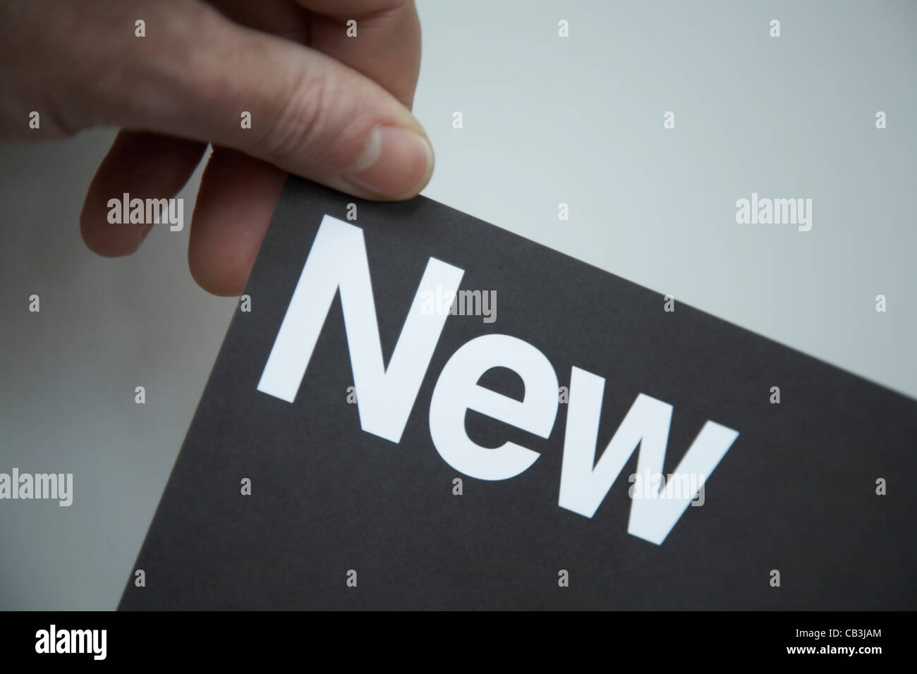 Hand holding card highlighting the word new Stock Photo - Alamy