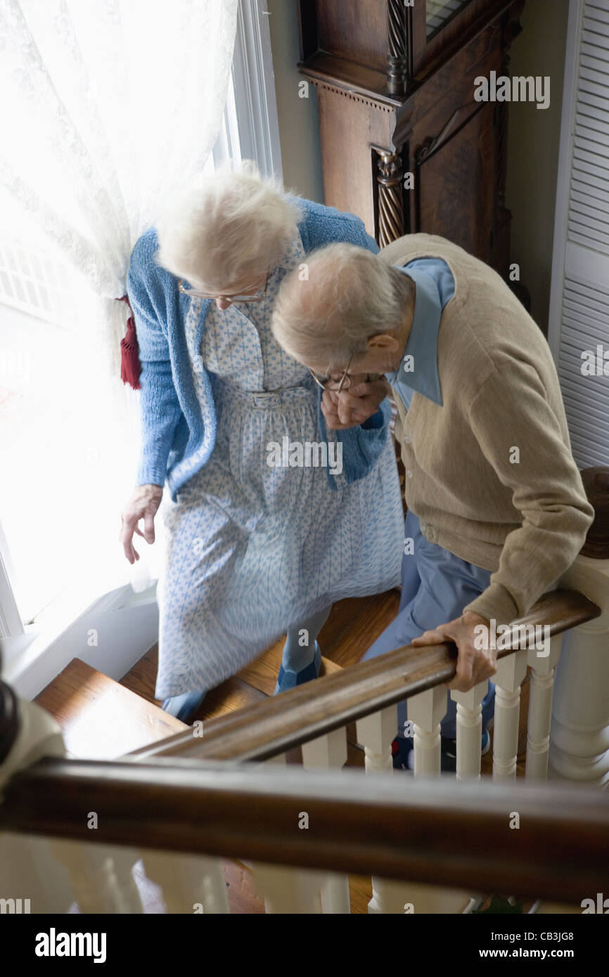 Senior couple helping one another carefully climb up stairs Stock Photo ...